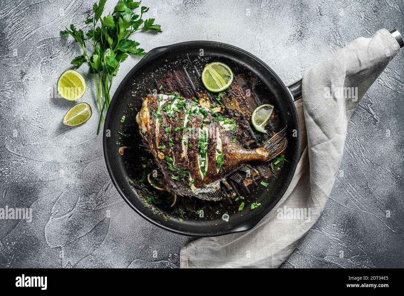 Grilled John Dory fish with lime and parsley in a pan. Gray background ...