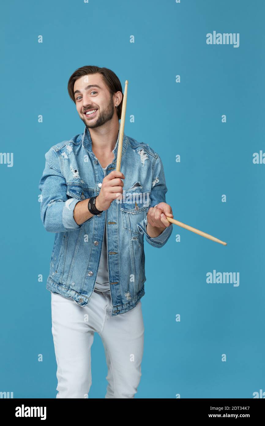handsome male drummer improvising isolated on blue studio background ...