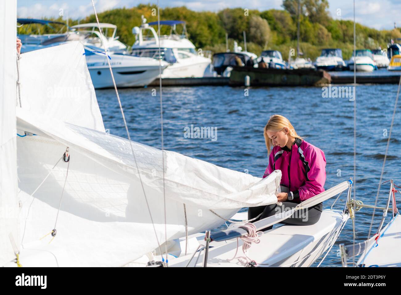 Cute blondes on the pier prepare a sailing yacht for a regatta, pull ...