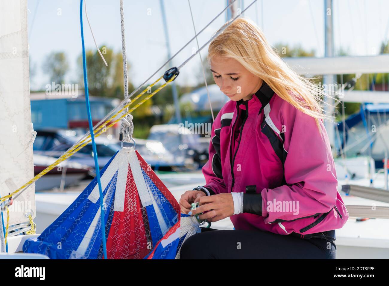 A young female sailing athlete sets a genaker sail on her white sports ...