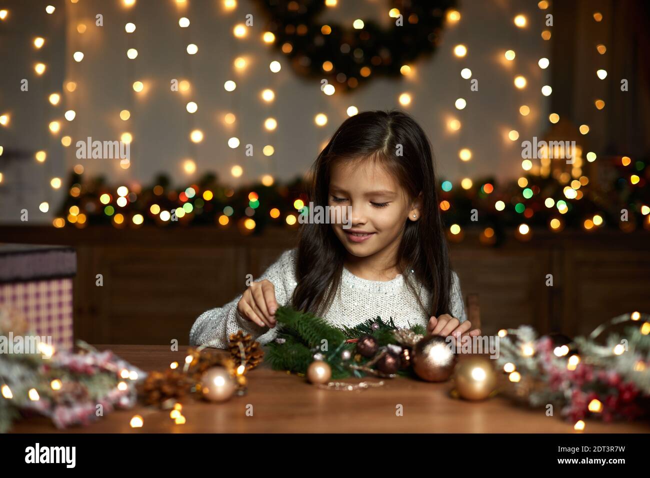 happy cute little child girl makes a handmade Christmas wreath at home ...