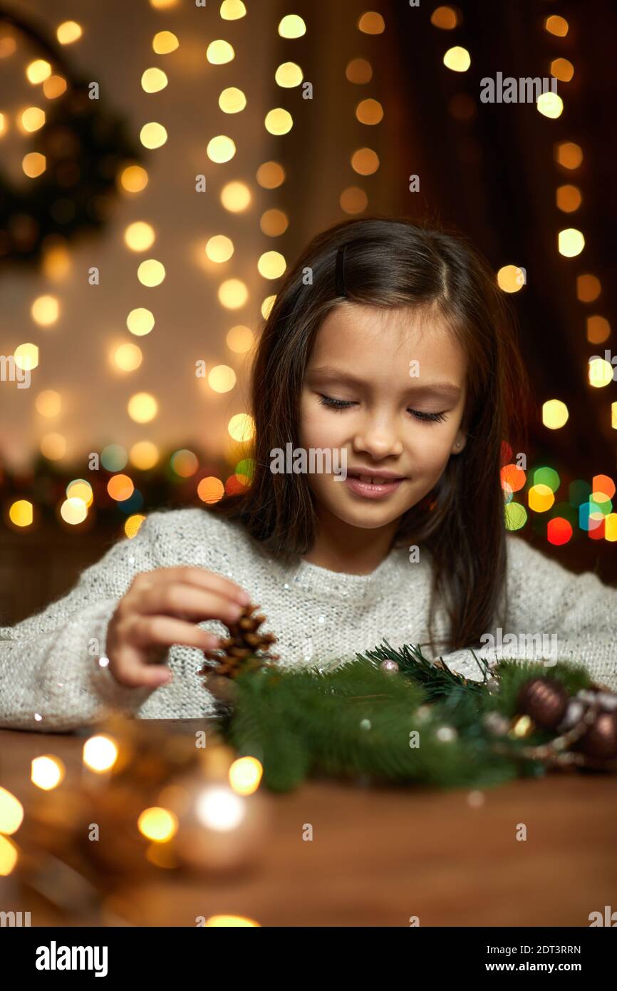 happy cute little child girl makes a handmade Christmas wreath at home ...