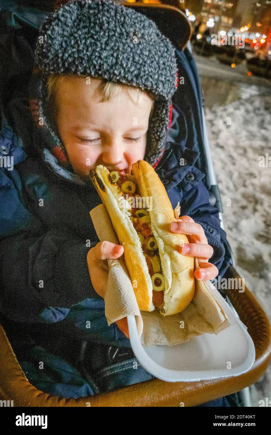 Cute little boy eating burger while sitting pram Stock Photo - Alamy