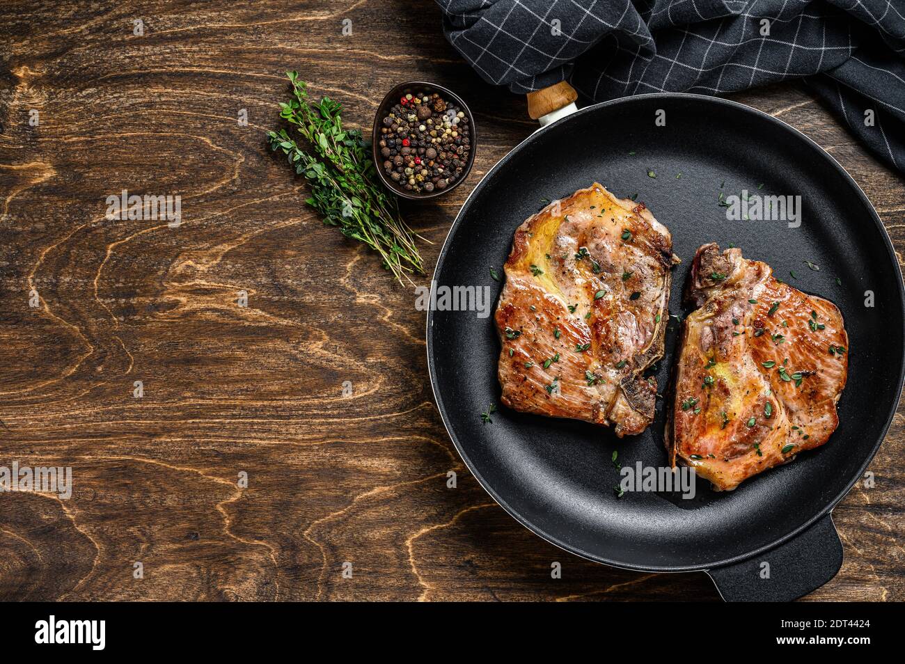Roasted pork steaks in frying pan from neck meat. Dark wooden ...