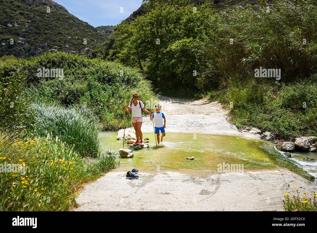 Mother and son crossing a stream in forest Stock Photo - Alamy