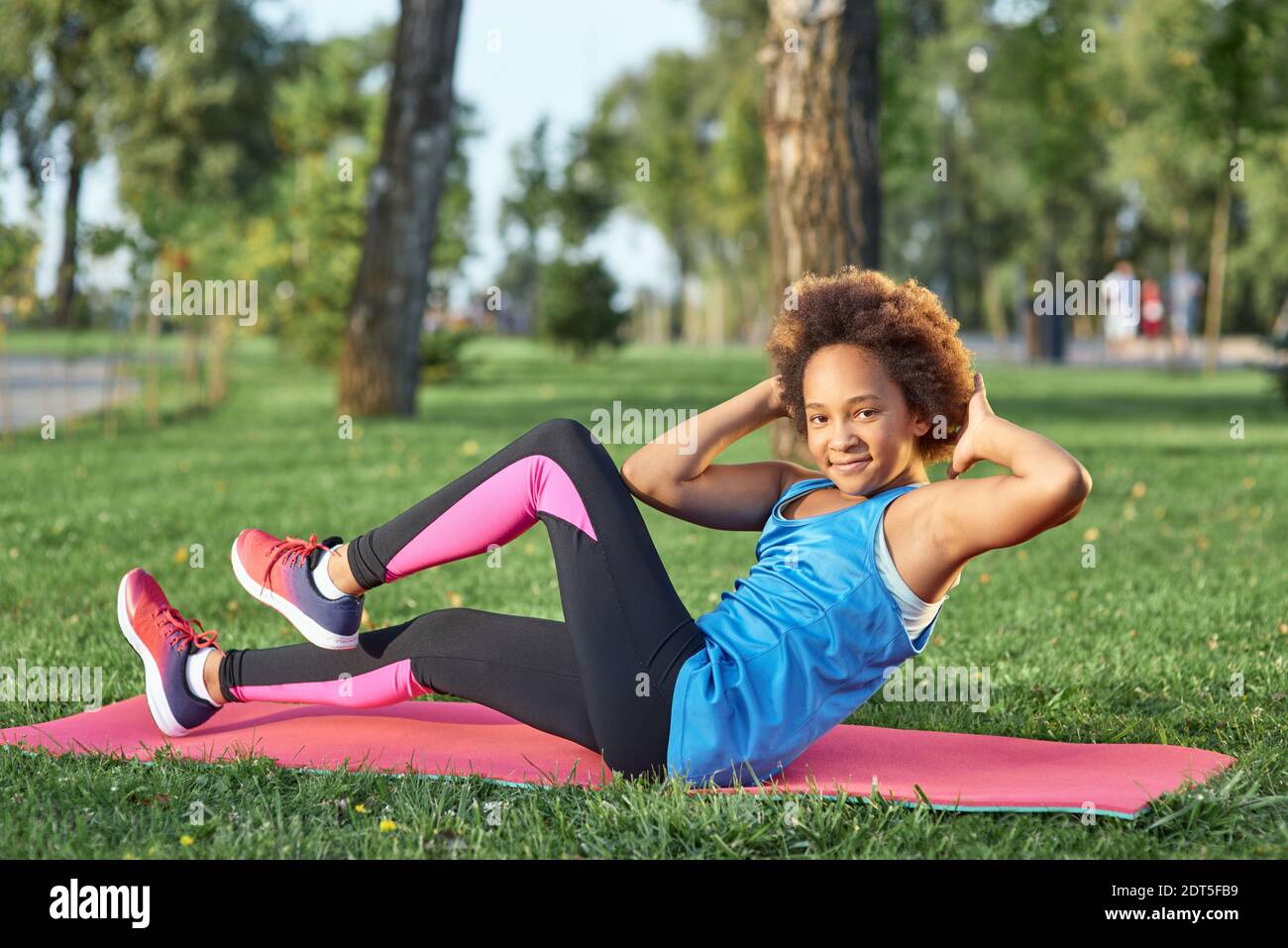 Adorable little girl in sportswear doing exercise in park Stock Photo ...