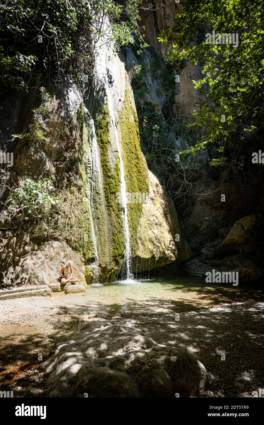 Woman sitting on rock beside waterfall Stock Photo - Alamy