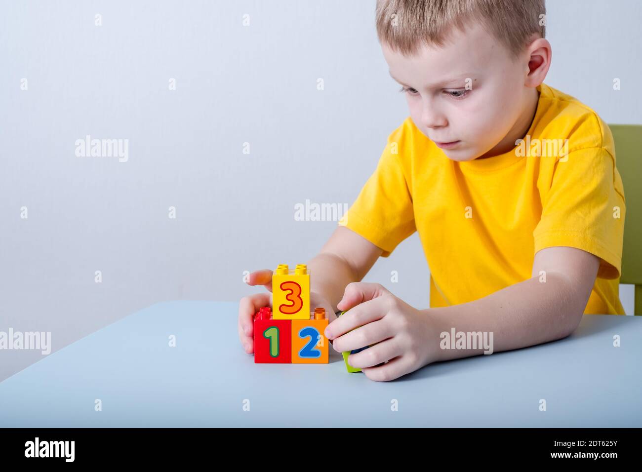 The child playing with cubes with numbers on the table.On a white ...