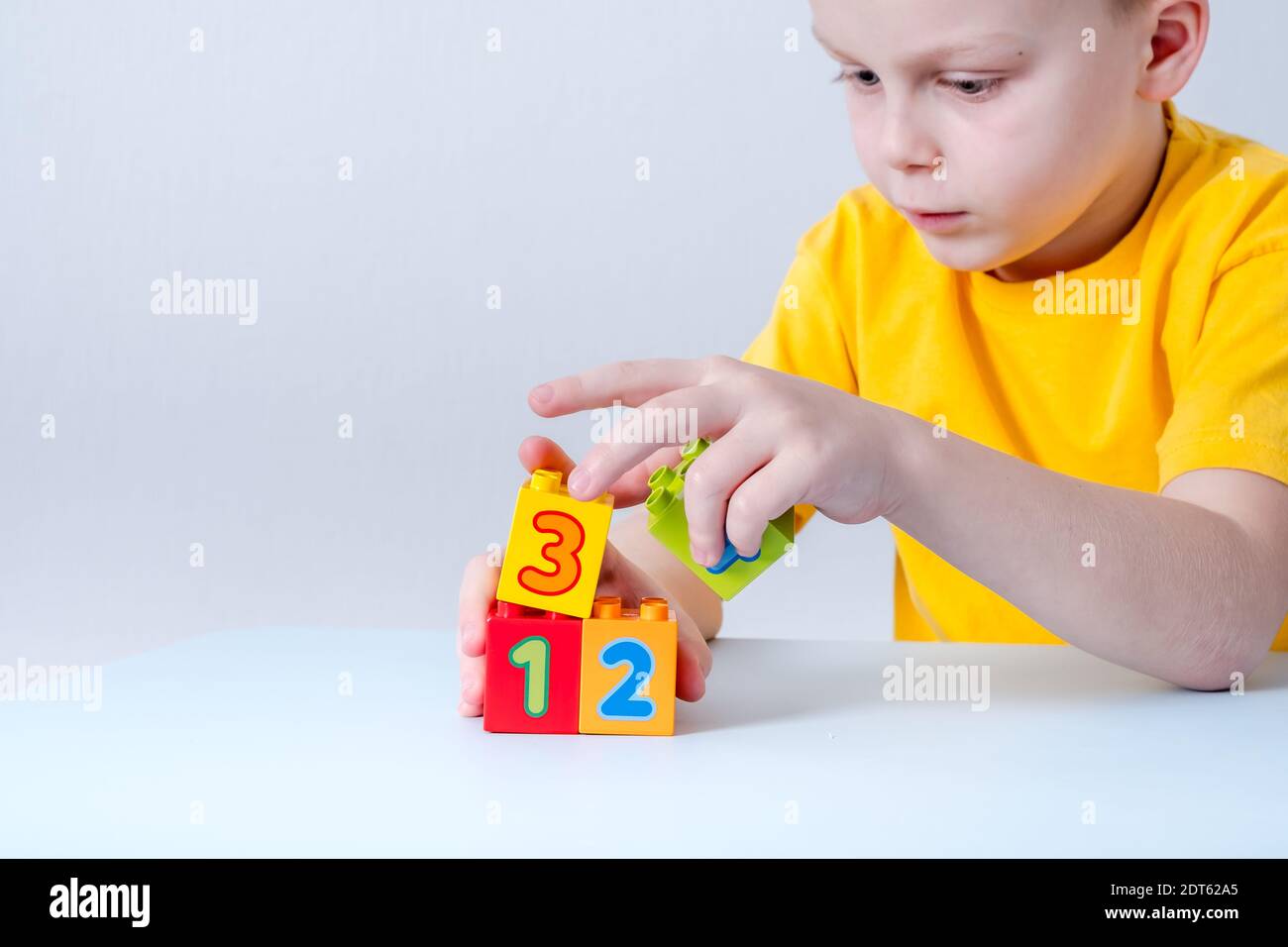 The child playing with cubes with numbers on the table.On a white ...
