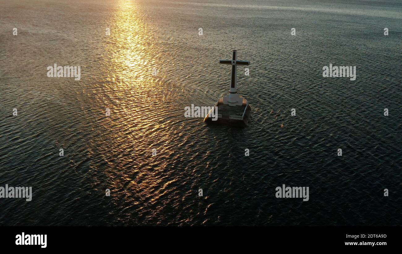 Catholic cross in sunken cemetery in the sea at sunset, aerial drone ...