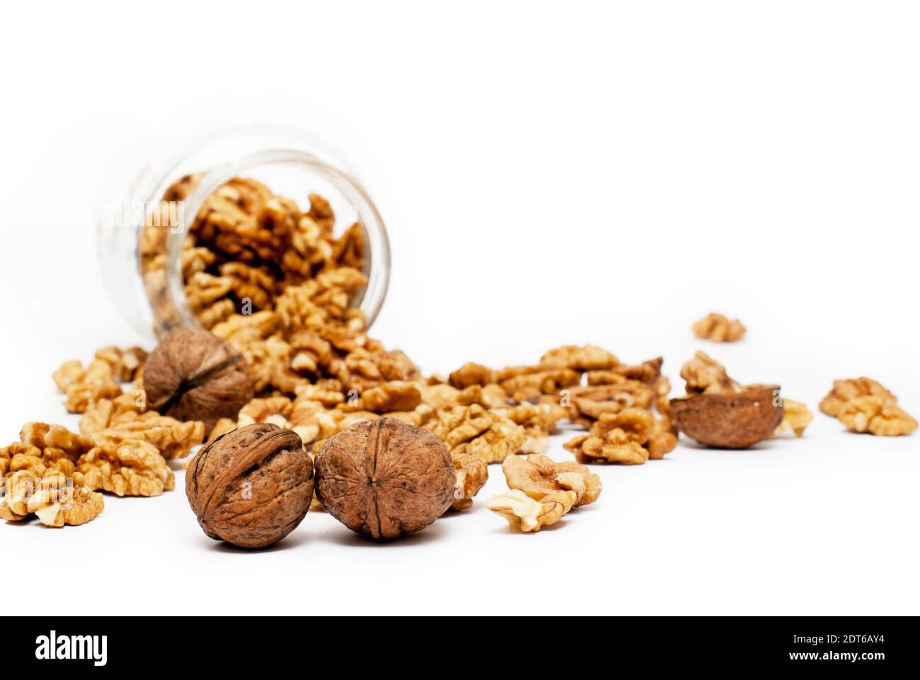 Jar of wallnuts with lots of wallnuts spilled on the floor, white ...