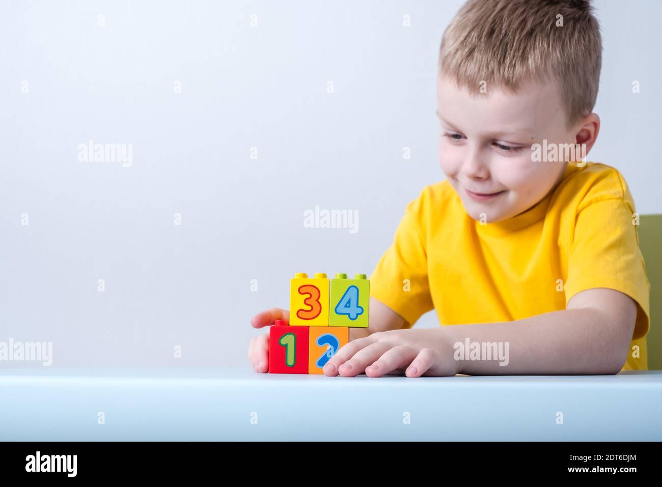 The child playing with cubes with numbers on the table.On a white ...