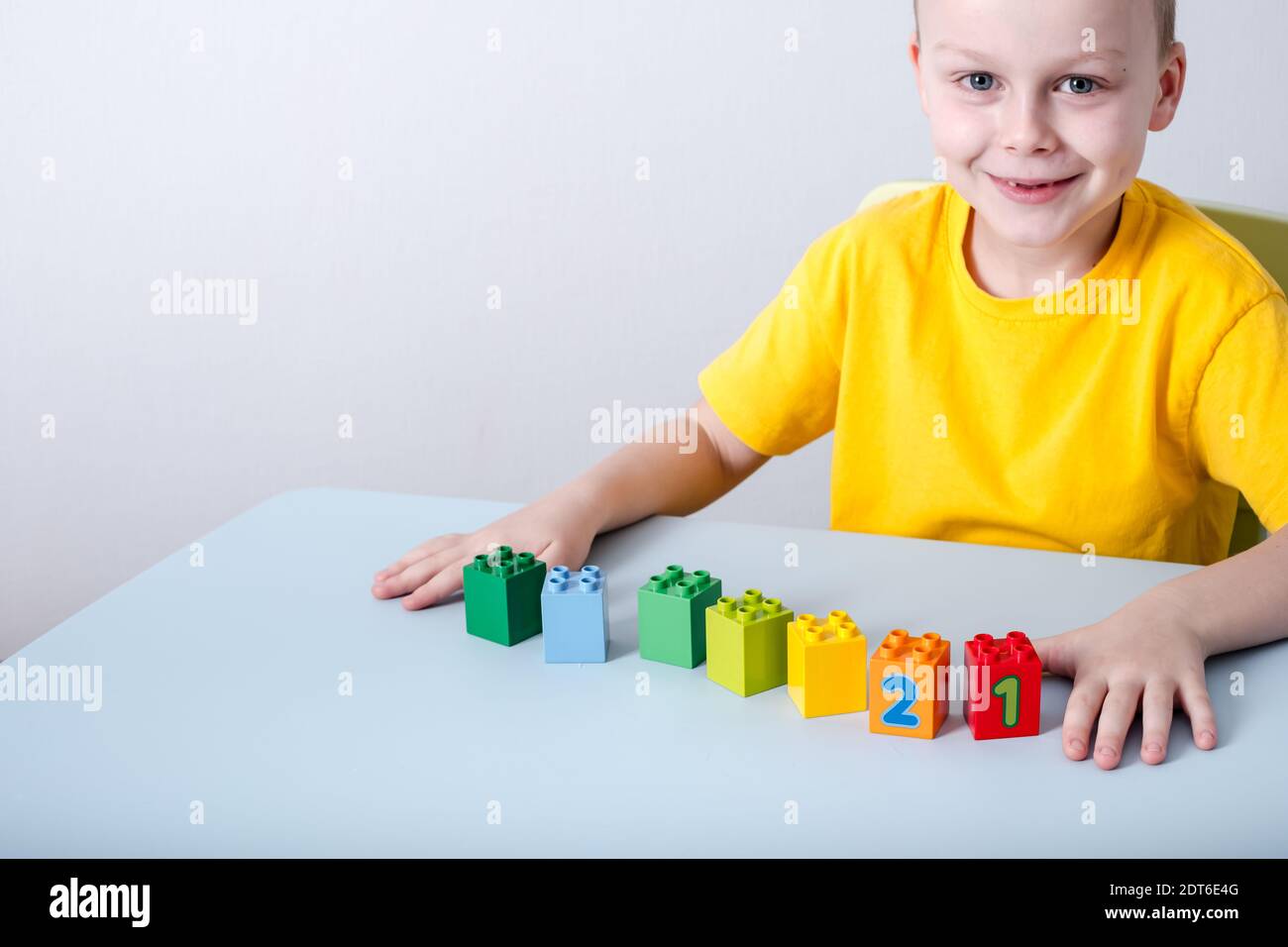 The child playing with cubes with colorful numbers on the table. On a ...