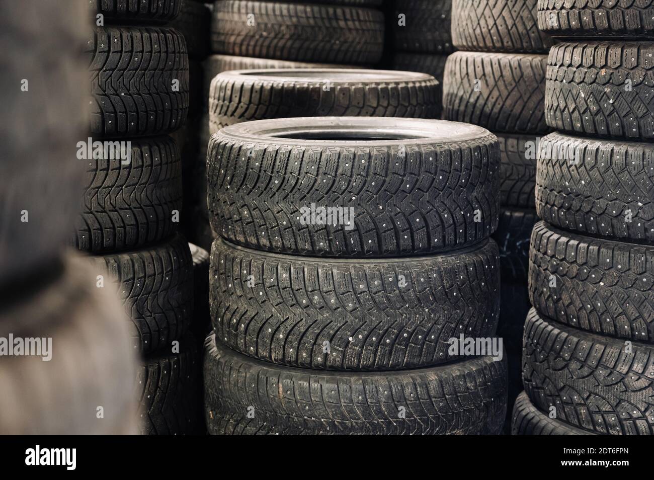 A pile of used spiked tires and treads in a car warehouse. stack of old ...