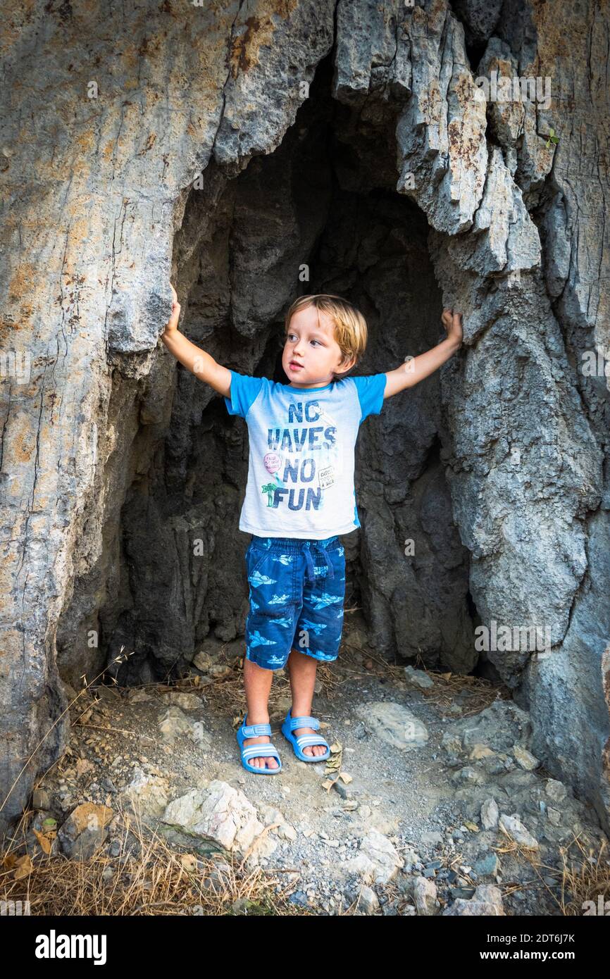 Little boy standing inside rock formation Stock Photo - Alamy