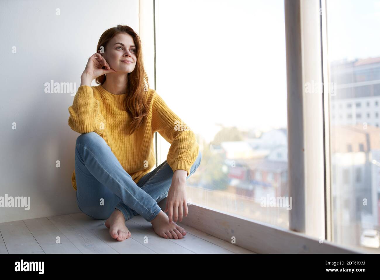 pretty woman sits on the windowsill and looks out the window rest charm ...