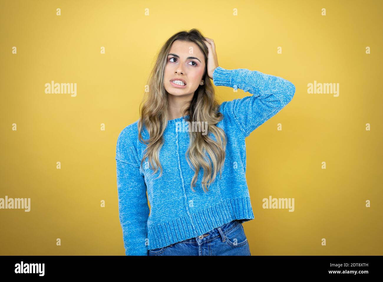 Pretty blonde woman with long hair standing over yellow background ...