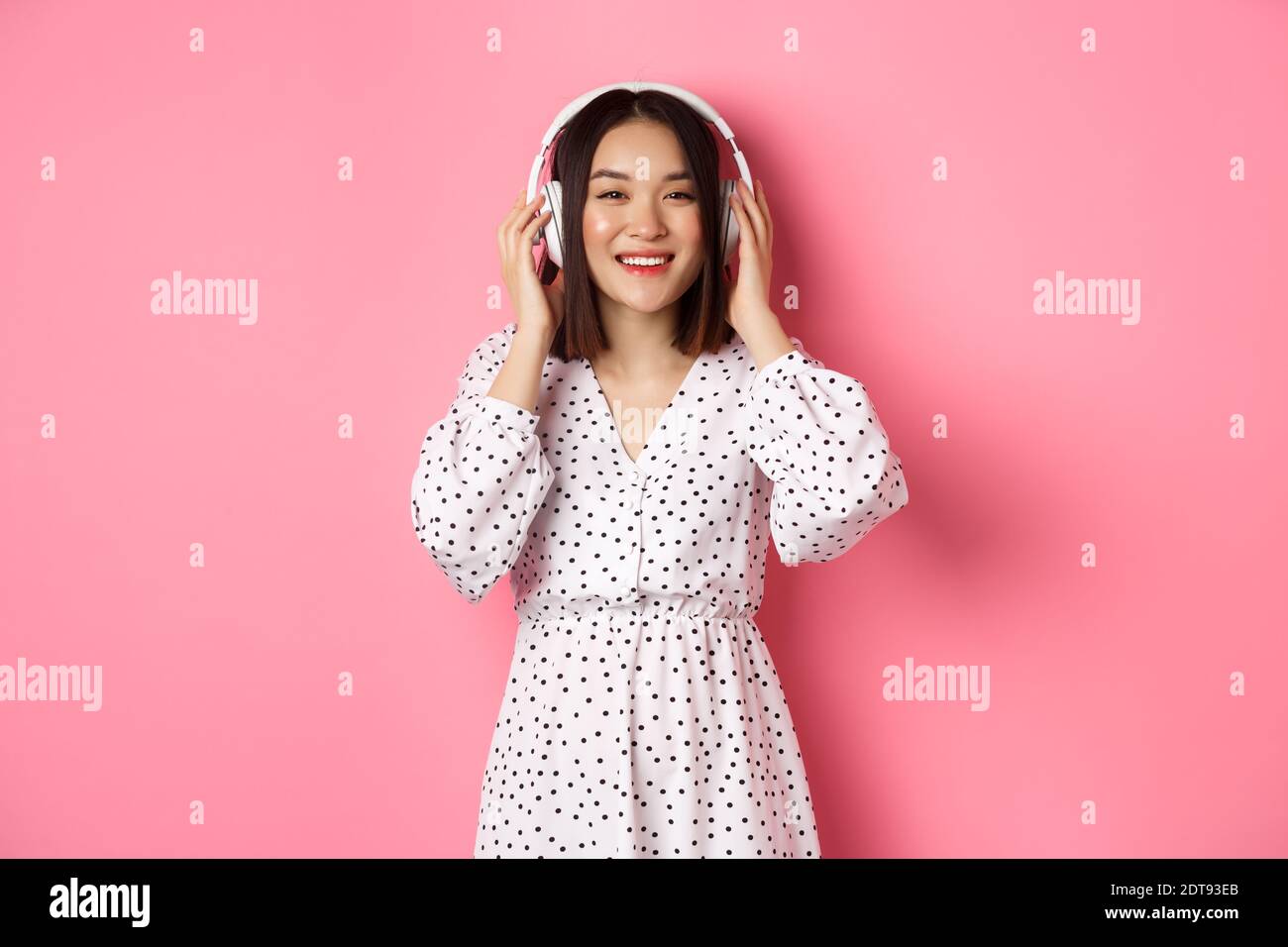 Romantic asian woman smiling happy, listening music in headphones and ...