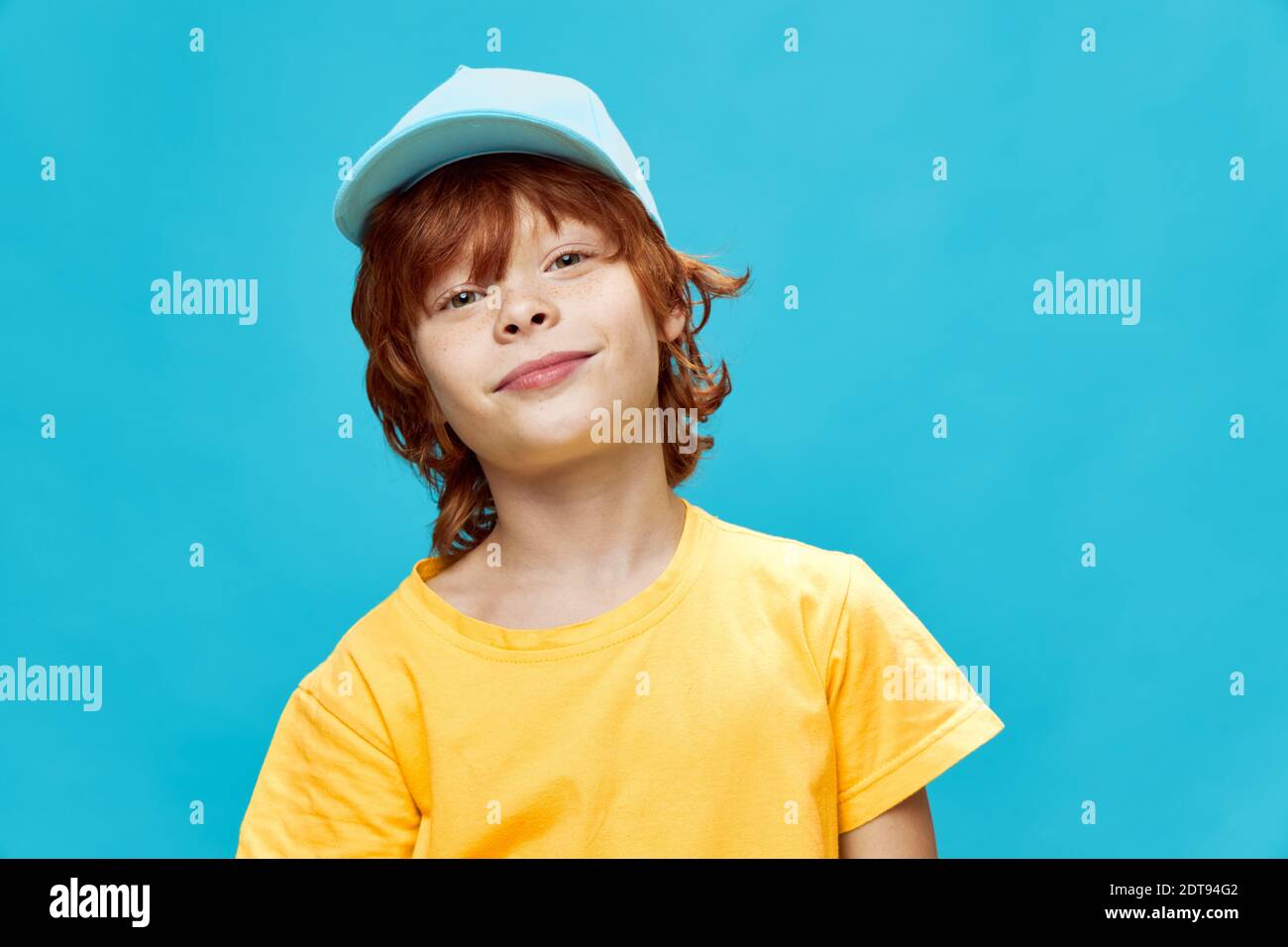 Red-haired boy with a cap on his head tilting his head to one side ...