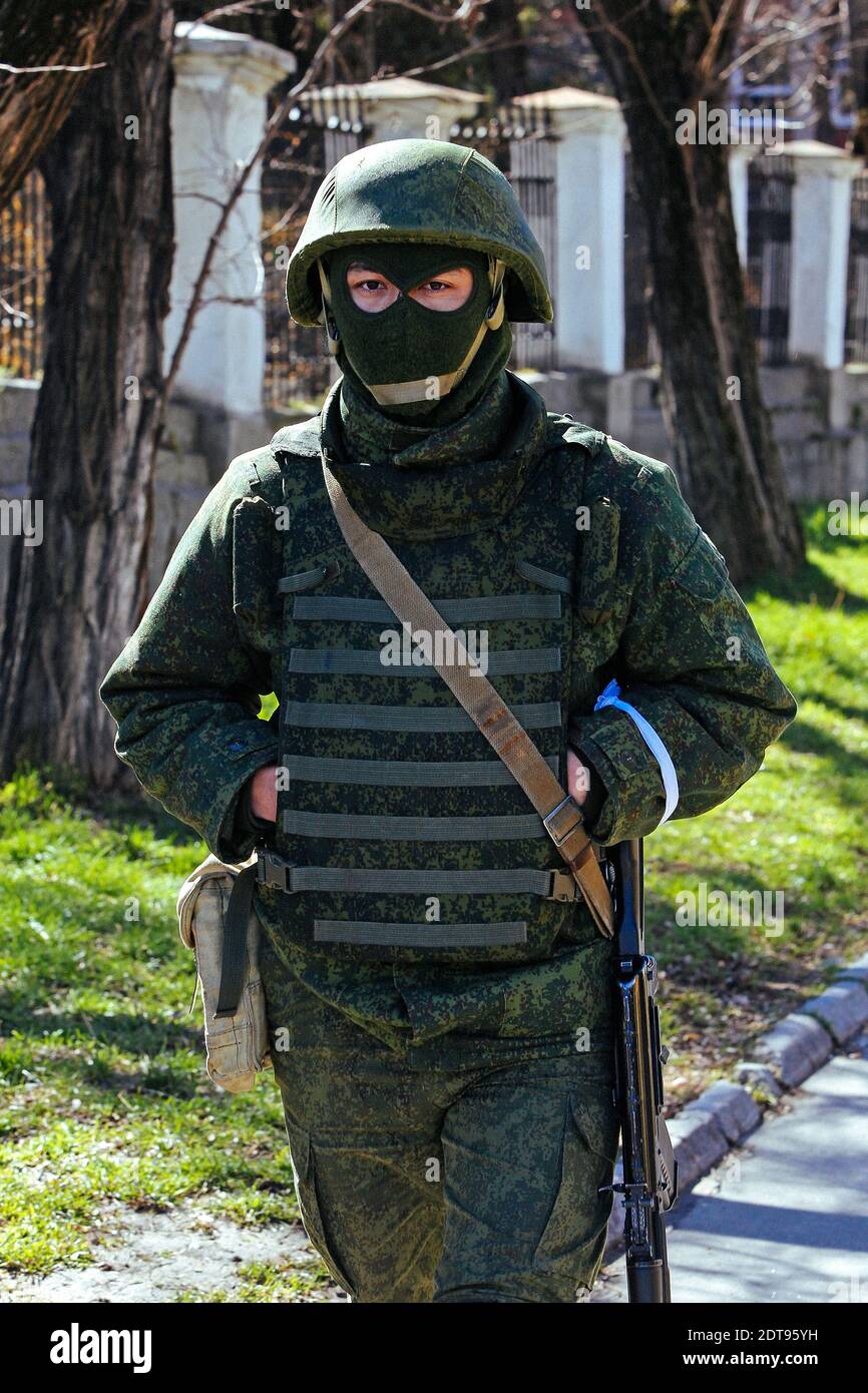 Armed men, believed to be Russian servicemen, stand guard outside a ...