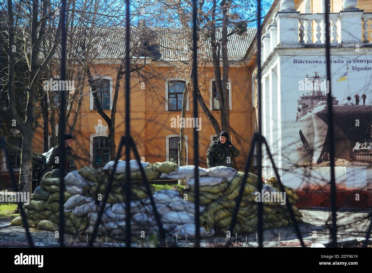 Armed men, believed to be Russian servicemen, stand guard outside a ...