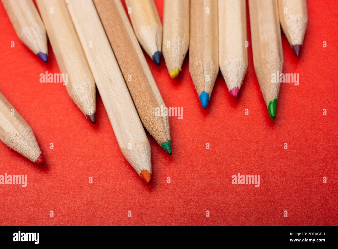 Colored pencils on red background. Many different colored pencils Stock ...