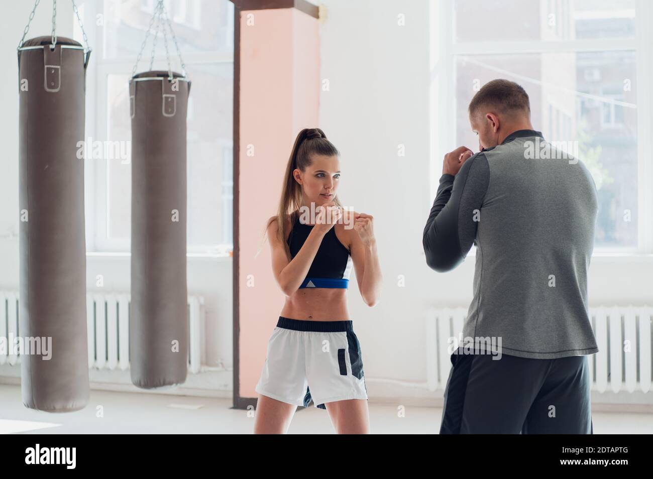 Cute girl learns kickboxing techniques in the gym with an experienced ...