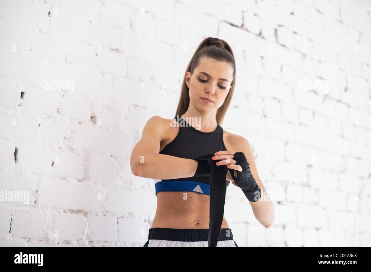 A pretty young athlete wraps a boxing bandage around her arm before ...