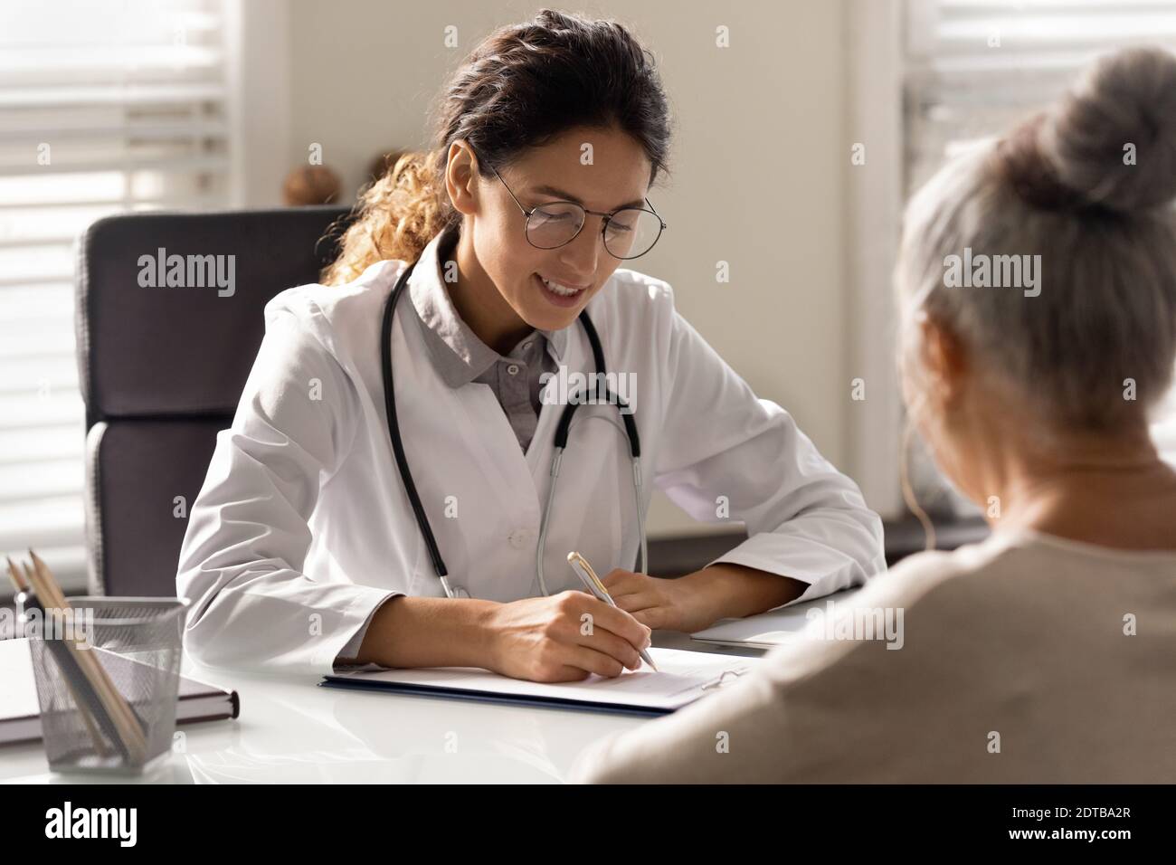 Female doctor write prescription to elderly patient Stock Photo - Alamy