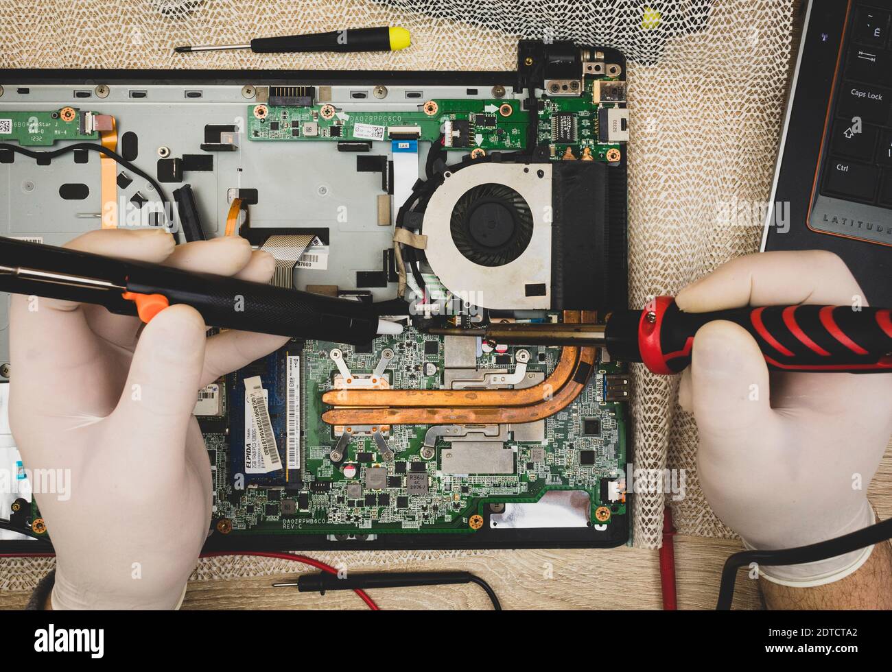 Hand of a master holding a soldering iron and suction on a computer ...