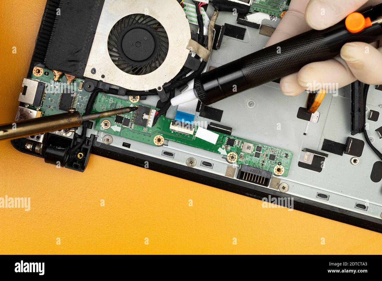 Hand of a master holding a soldering iron and suction on a computer ...