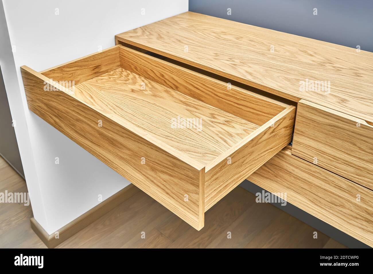 Stylish floating cabinet of natural wood with opened empty drawer near ...
