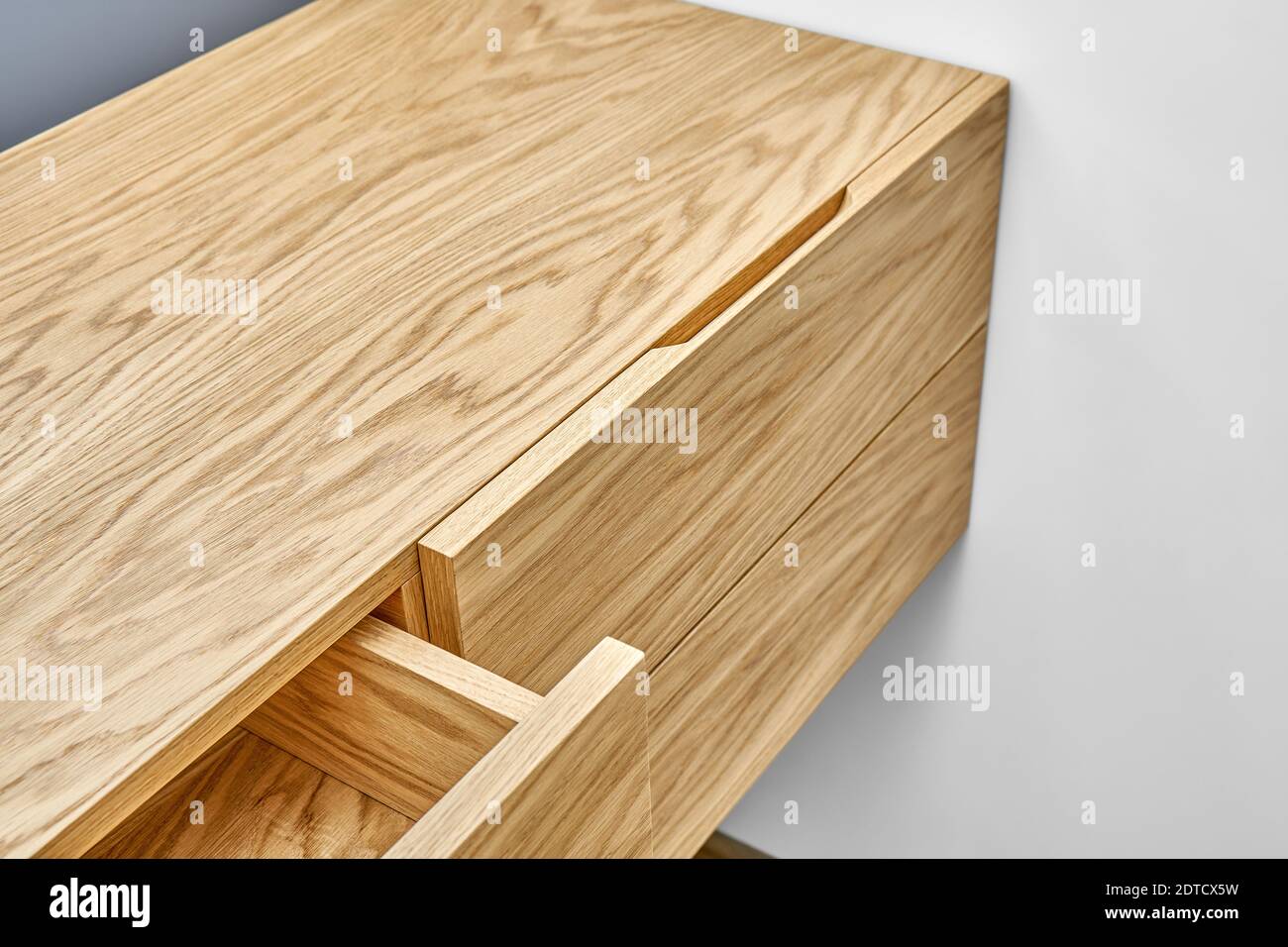 Stylish floating cabinet of natural wood with opened empty drawer near ...
