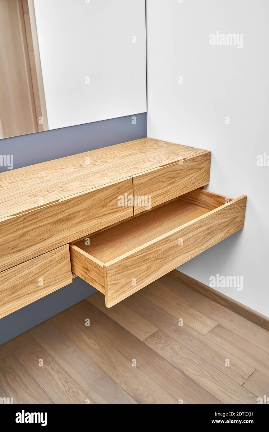 Stylish floating cabinet of natural wood with opened empty drawer near ...