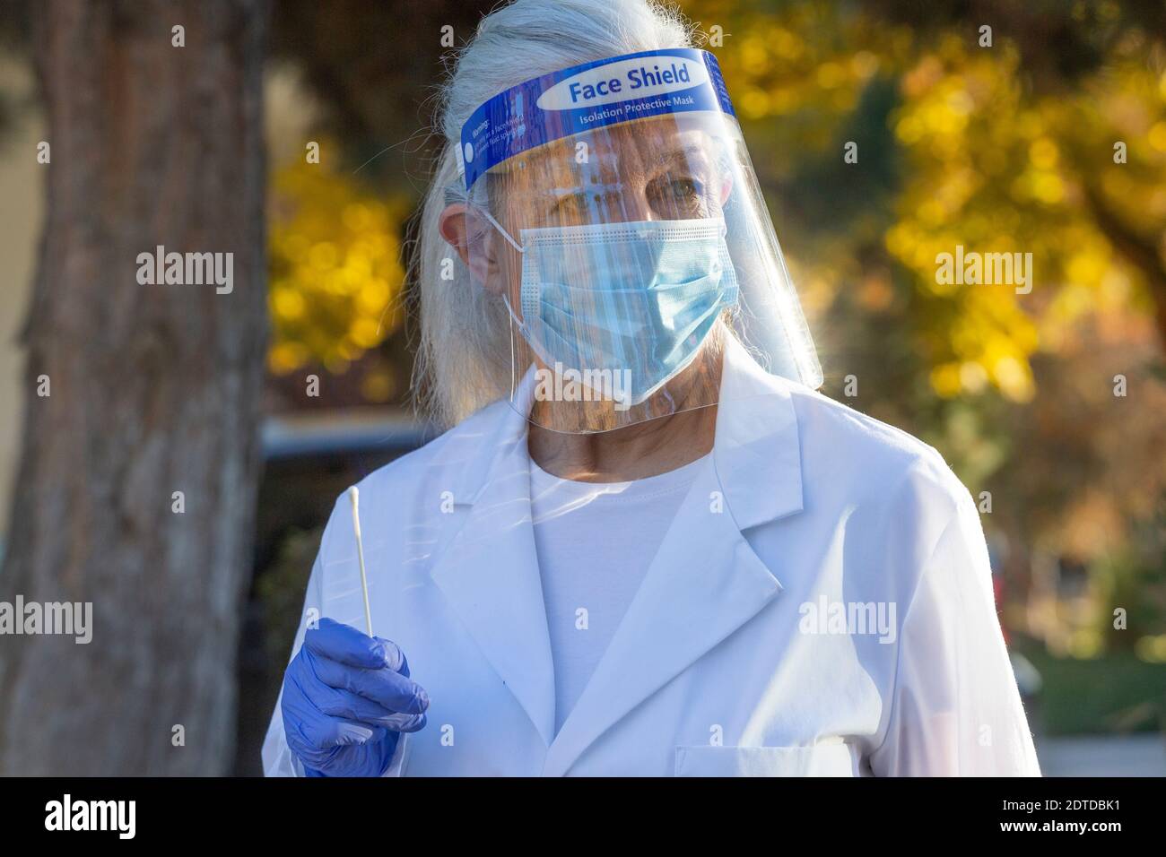 Female medical staff in protective clothing holding coronavirus swab ...