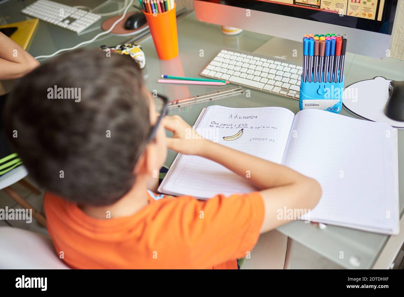 Boys (8-9) learning at home desk with notebook during Covid-19 lockdown ...