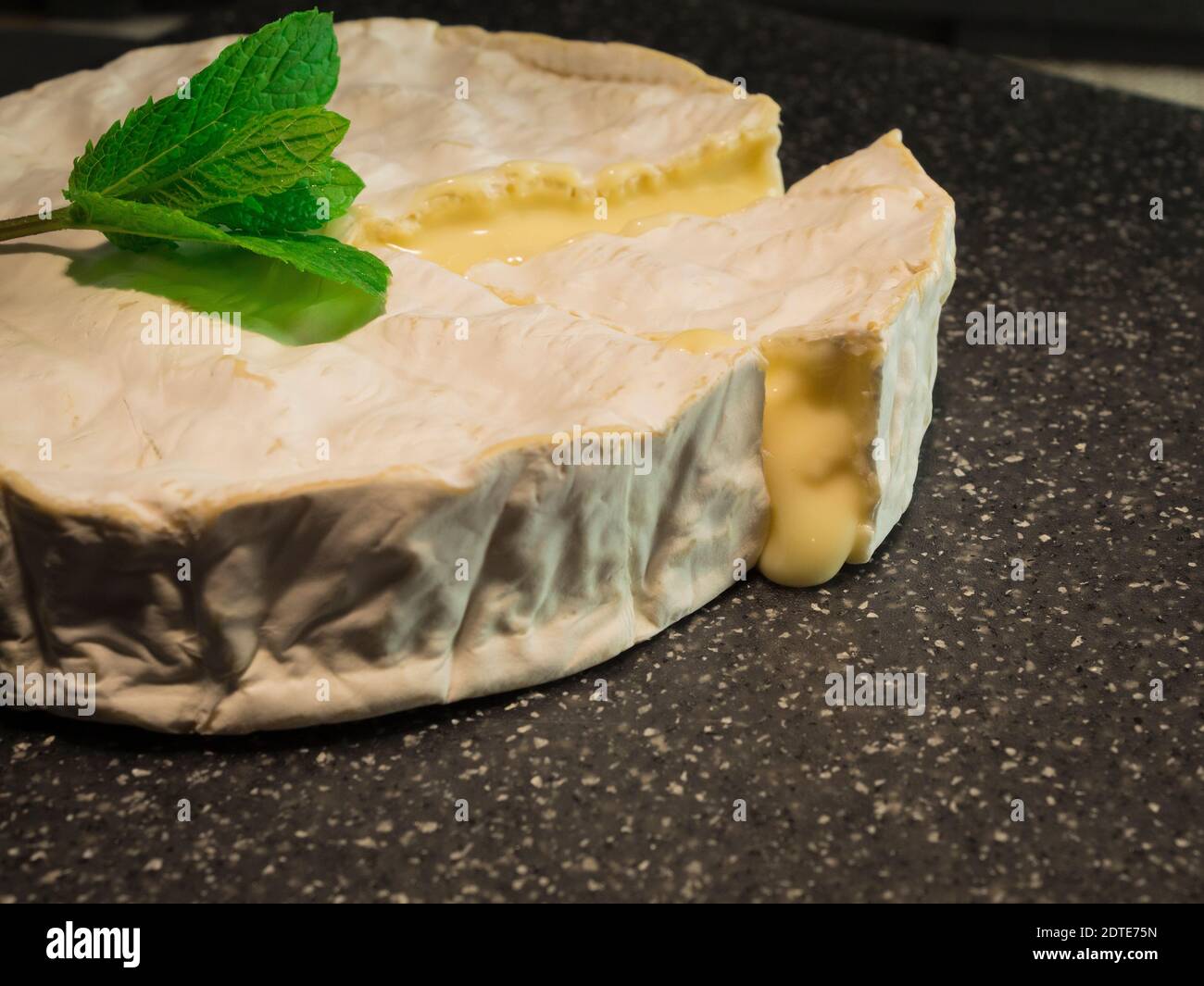 Sliced slice of Camembert cheese. Round cheese and fresh mint leaves ...