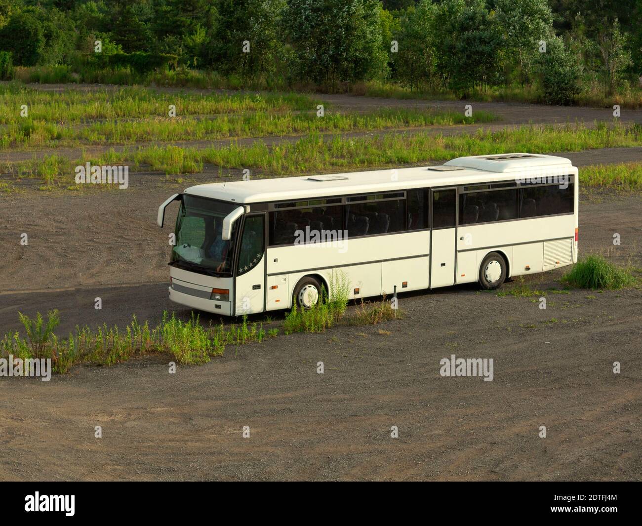 White bus stands alone in the field Big white bus in the parking lot ...
