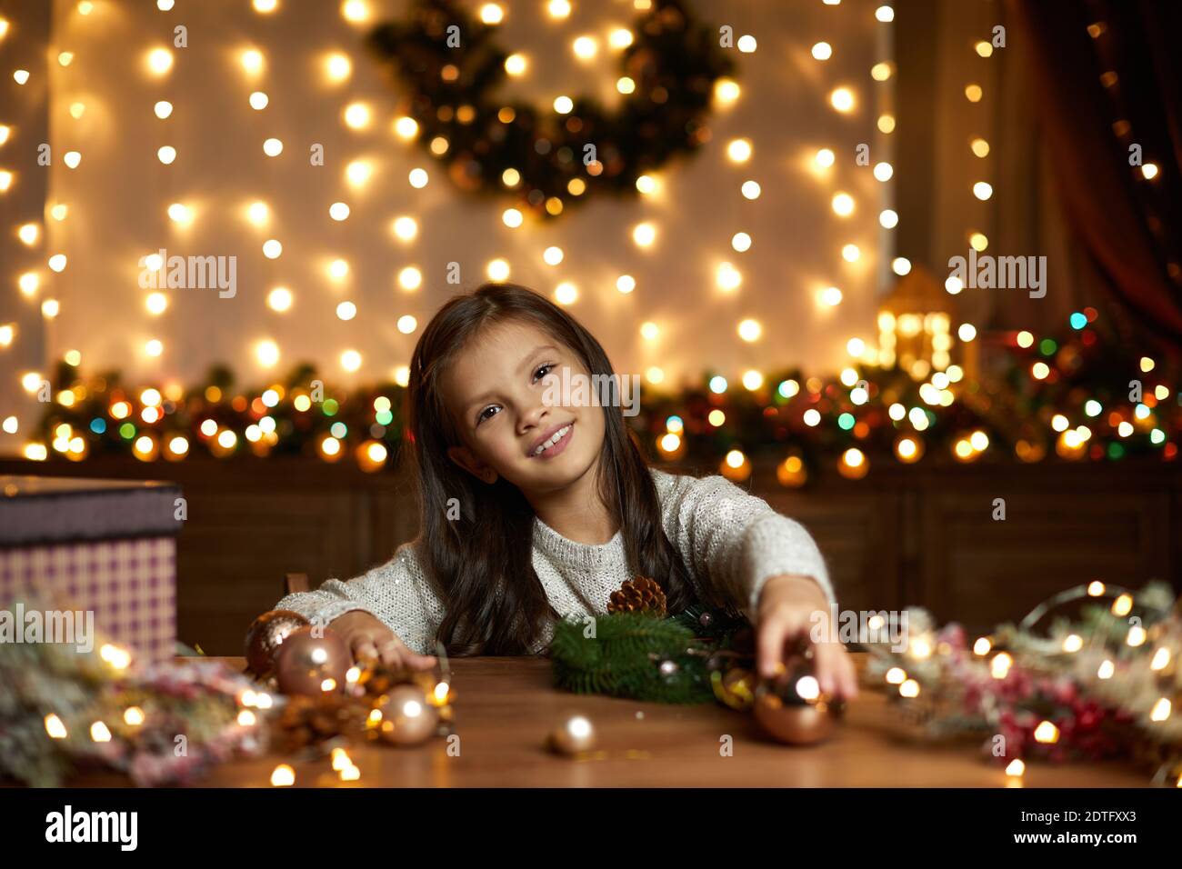 happy cute little child girl makes a handmade Christmas wreath at home ...