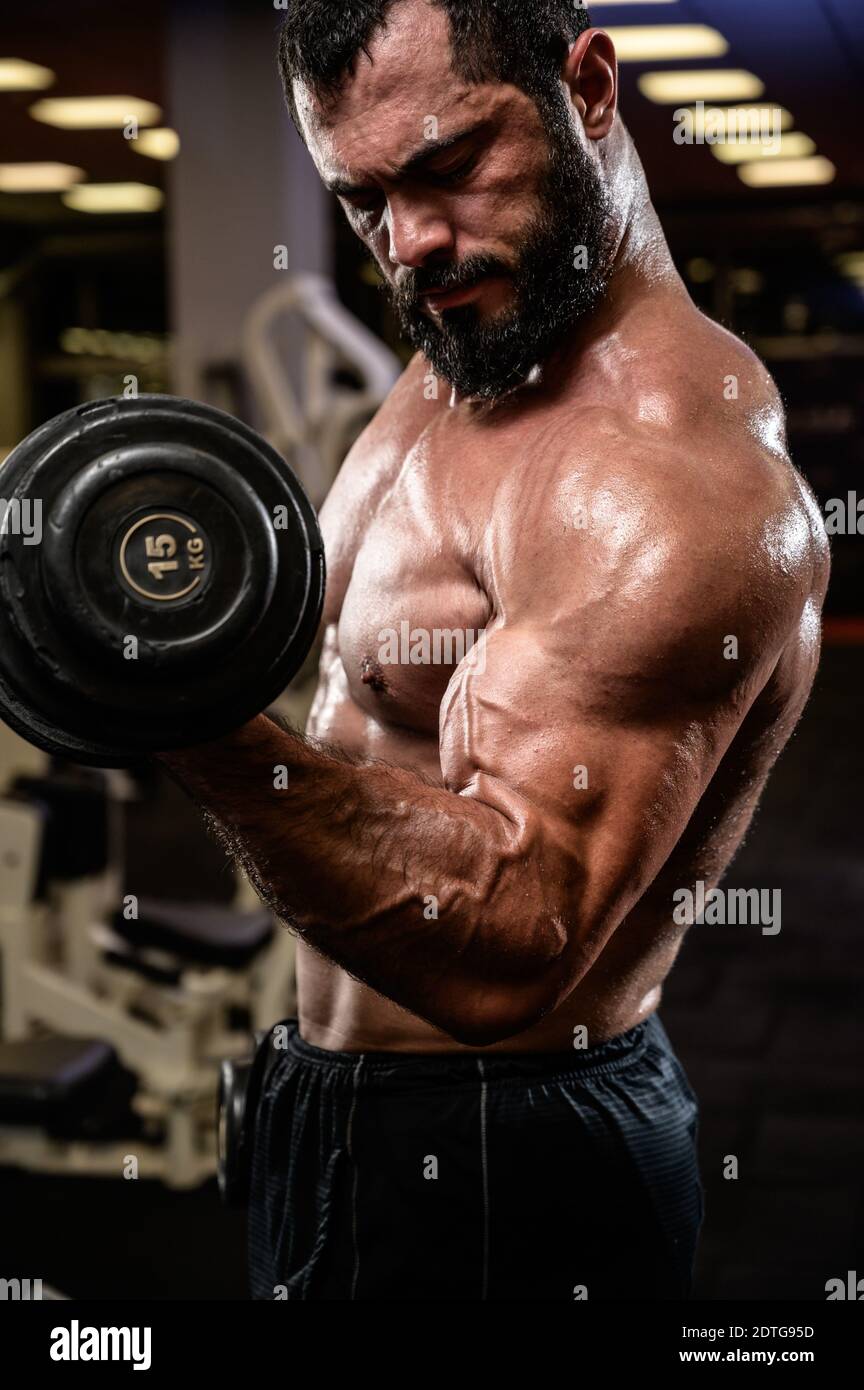 biceps heavy training with dumbbell by strong young athlete with beard ...