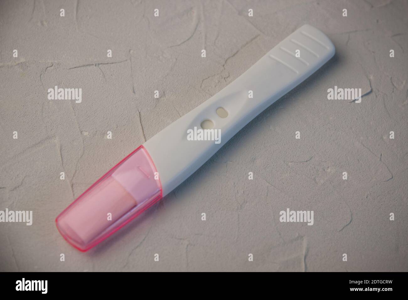 White pregnancy test with pink cover on grey concrete background. Close ...