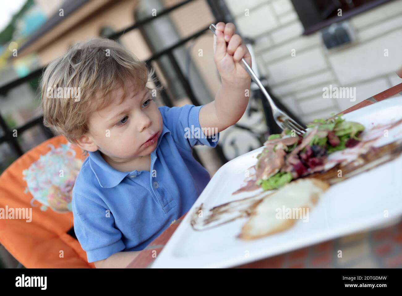 Hungry child has salad in a cafe Stock Photo - Alamy