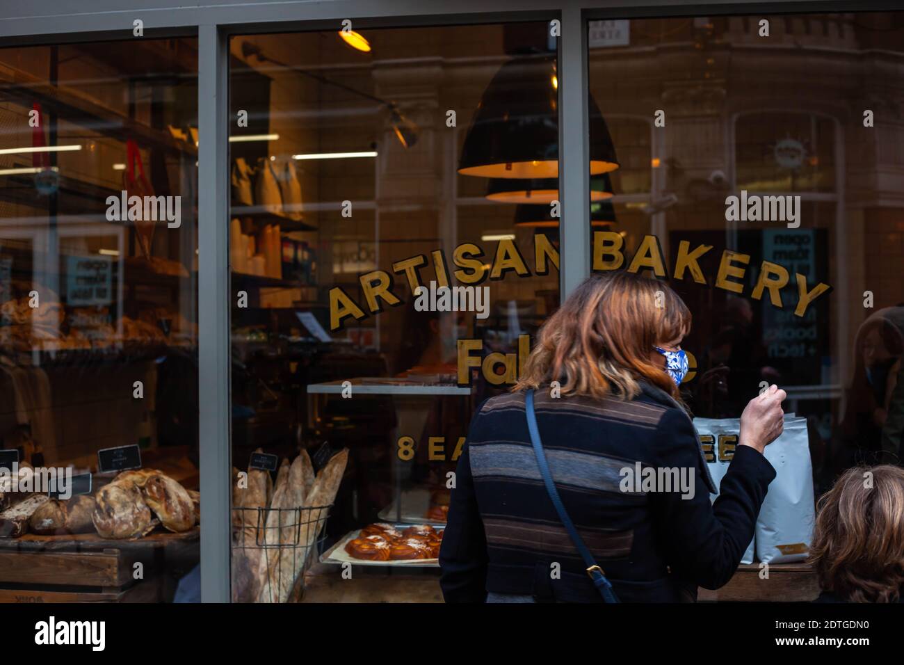 Rear view of adult woman wearing face covering and young child outside ...