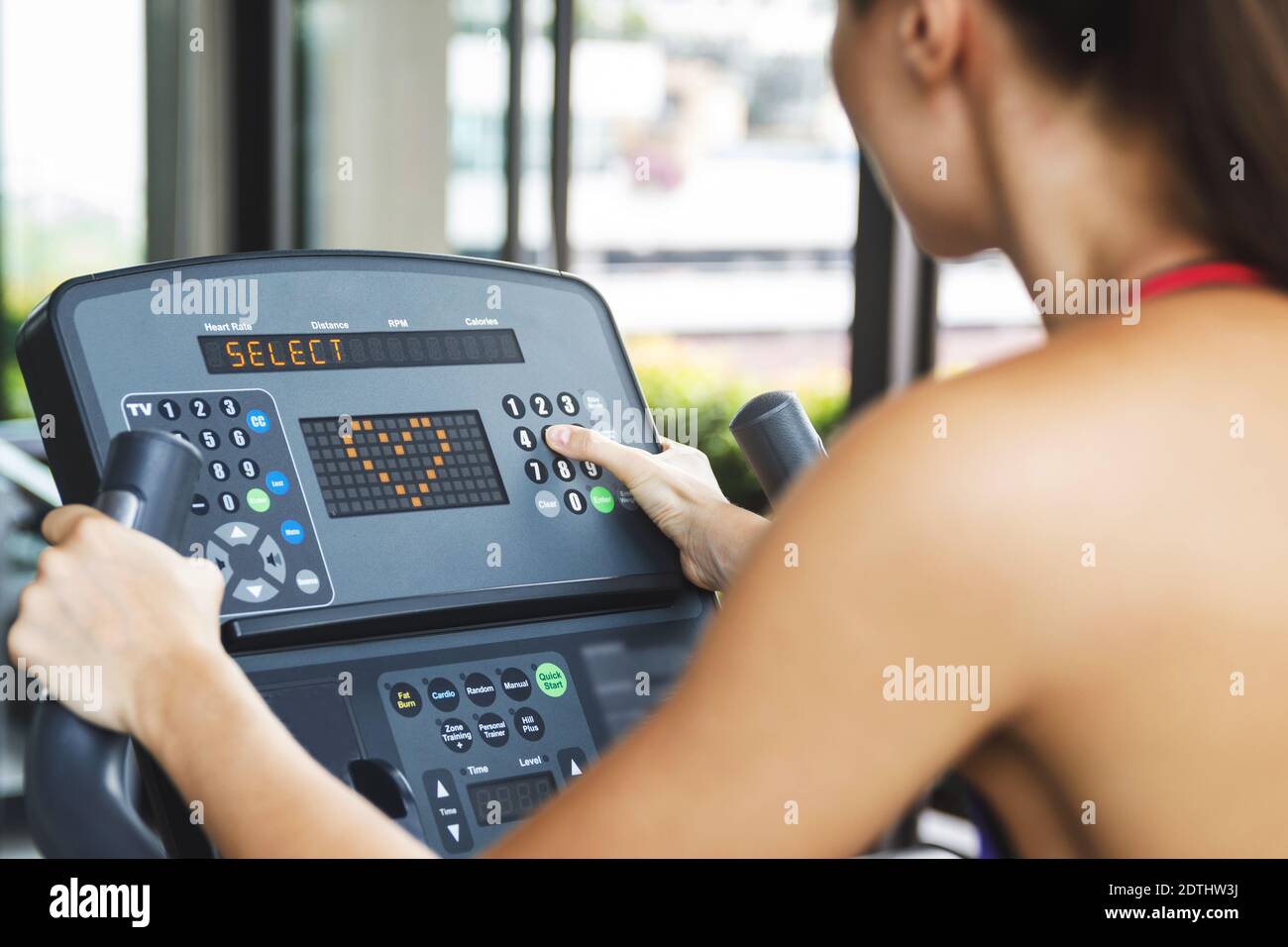 Fitness workout on stationary bike in the gym. Woman is setting up the ...