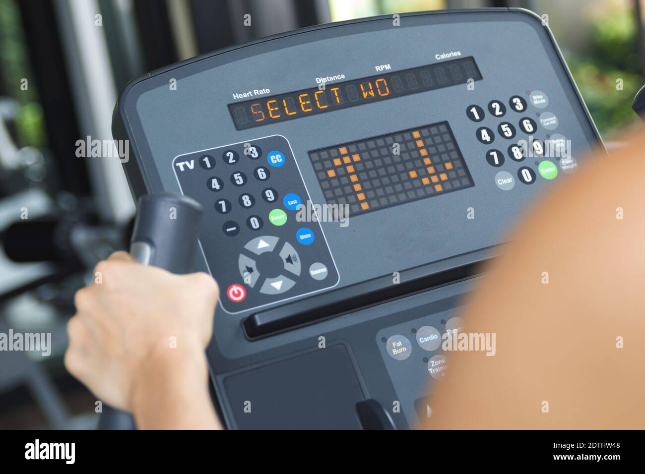 Fitness workout on stationary bike in the gym. Woman is setting up the ...