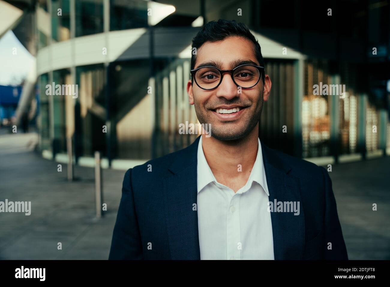 Mixed race businessman smiling walking standing outside office building ...