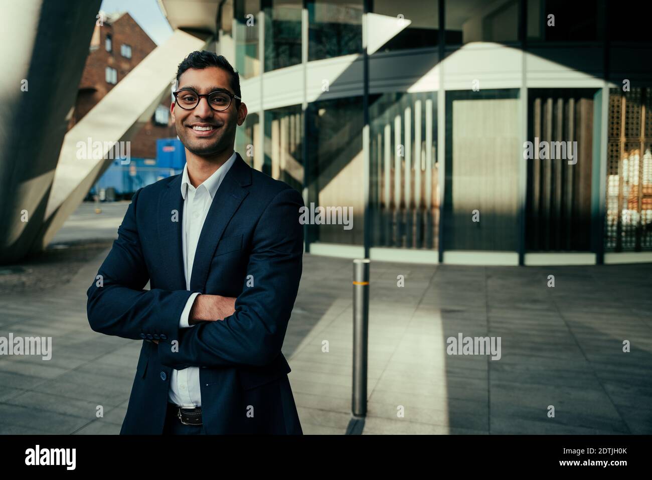 Mixed race businessman smiling standing with crossed arms in front of ...