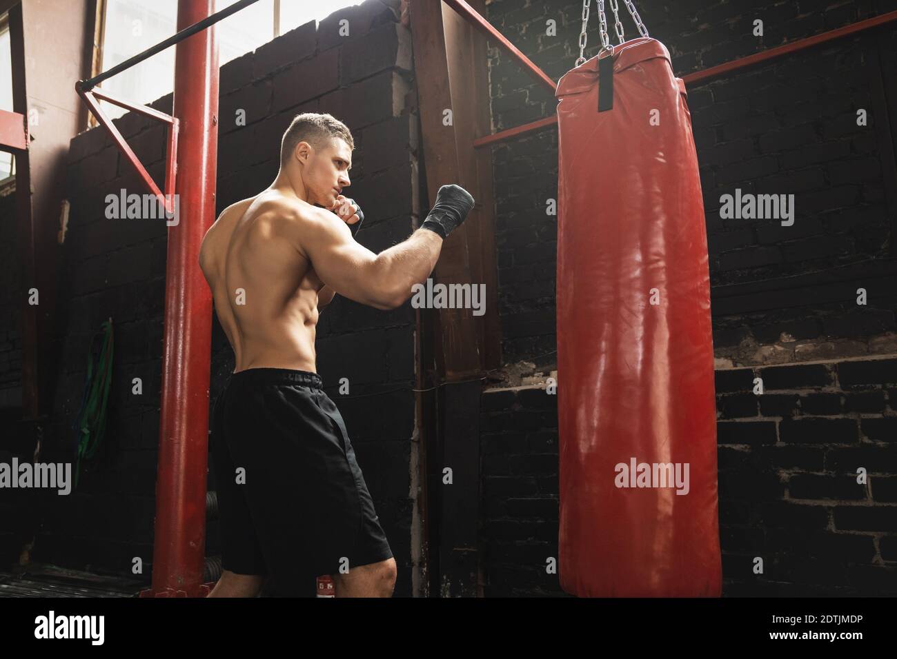 Strong young mma fighter and red punching bag in the gym Stock Photo ...