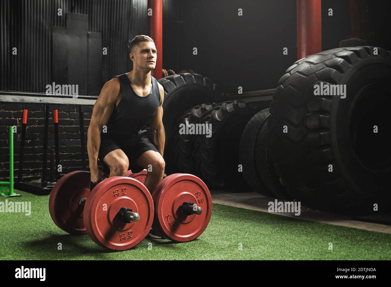 Young muscular sportsman doing farmer's walk exercise during his cross ...