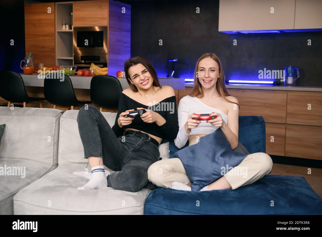 Two pretty girlfriends playing with excitement video games at home ...